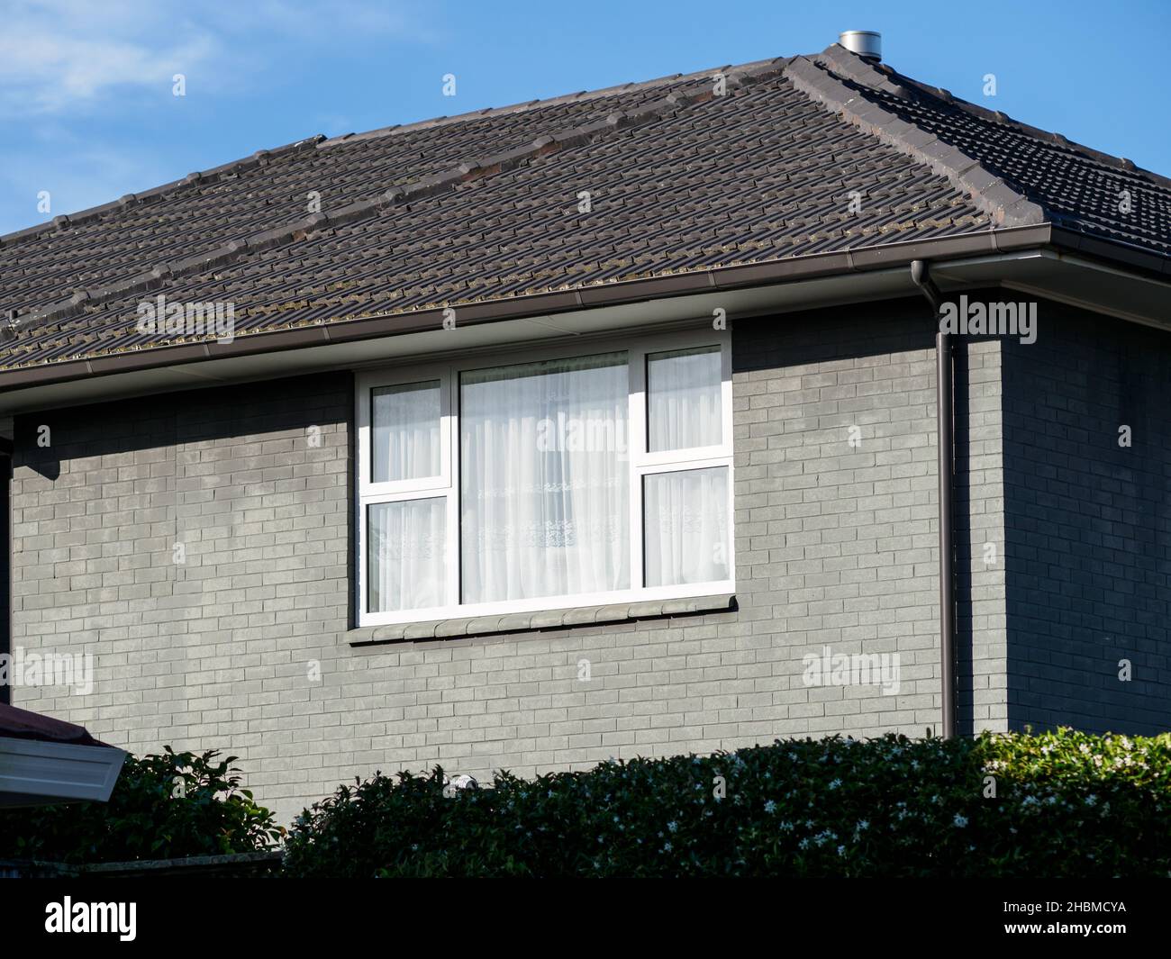 View of detached house with white window frame on gray brick wall and ...