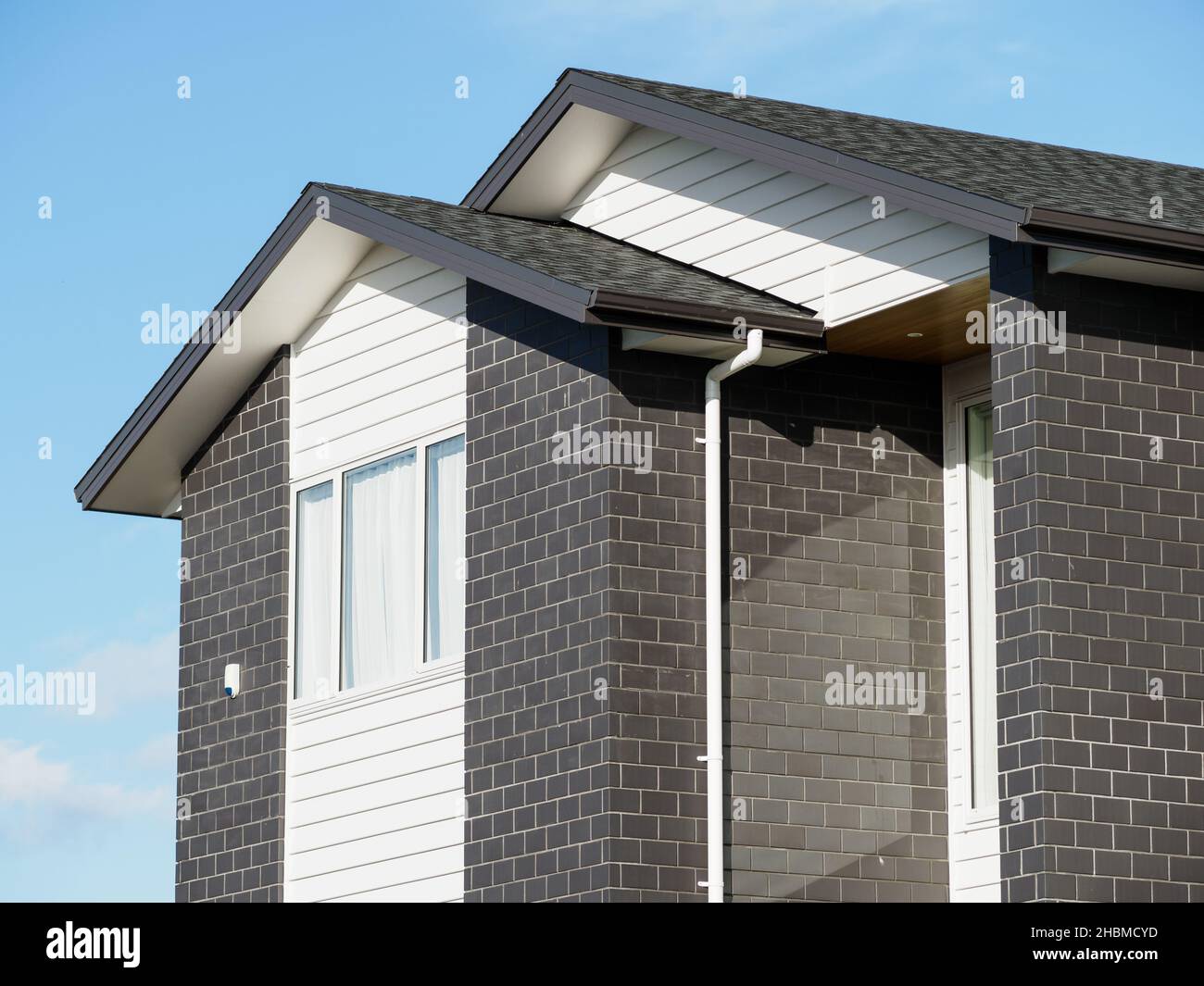 View of detached house with white window frame on gray brick wall and ...