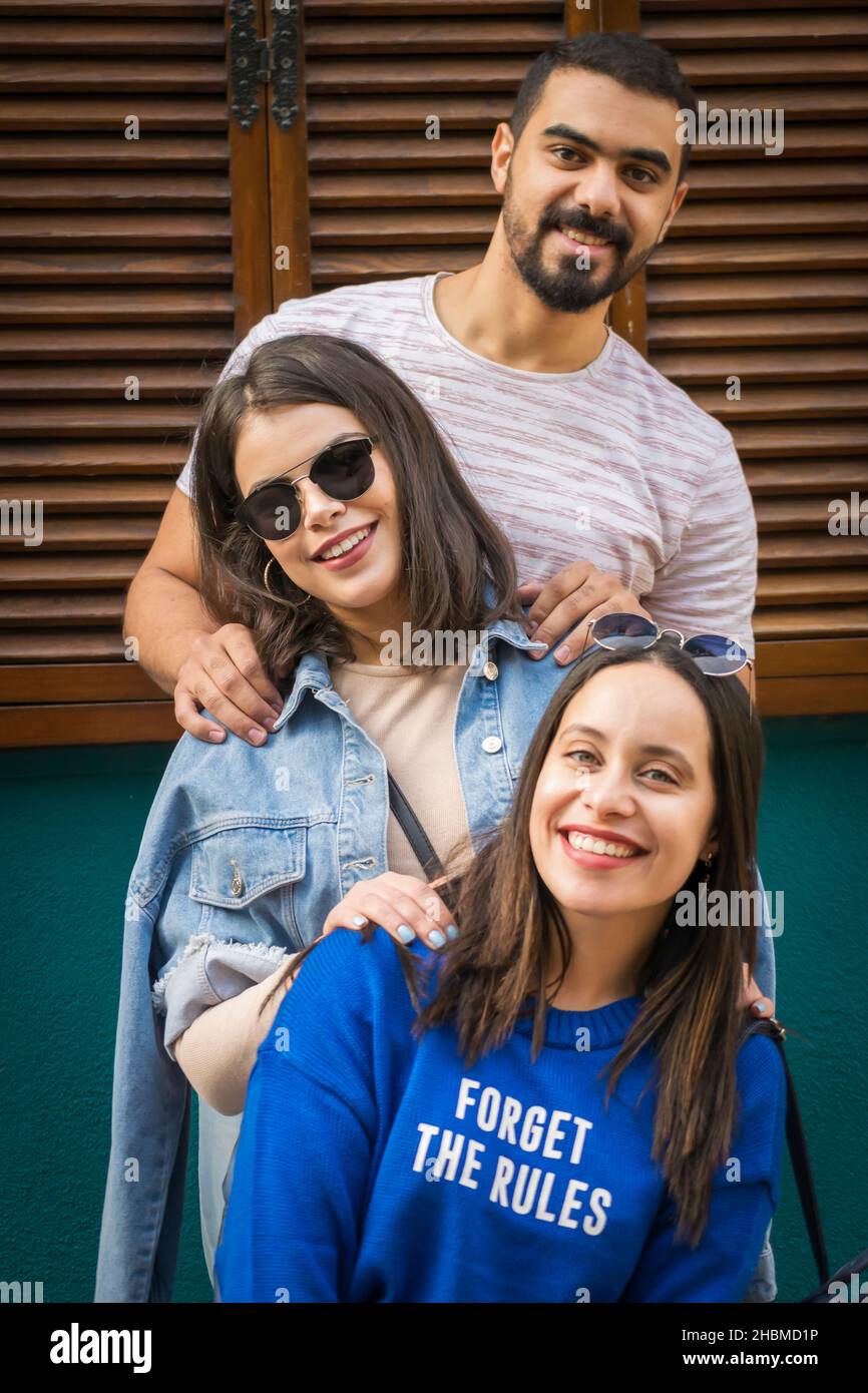 three happy friends are being relaxed and smiley posing for a group ...