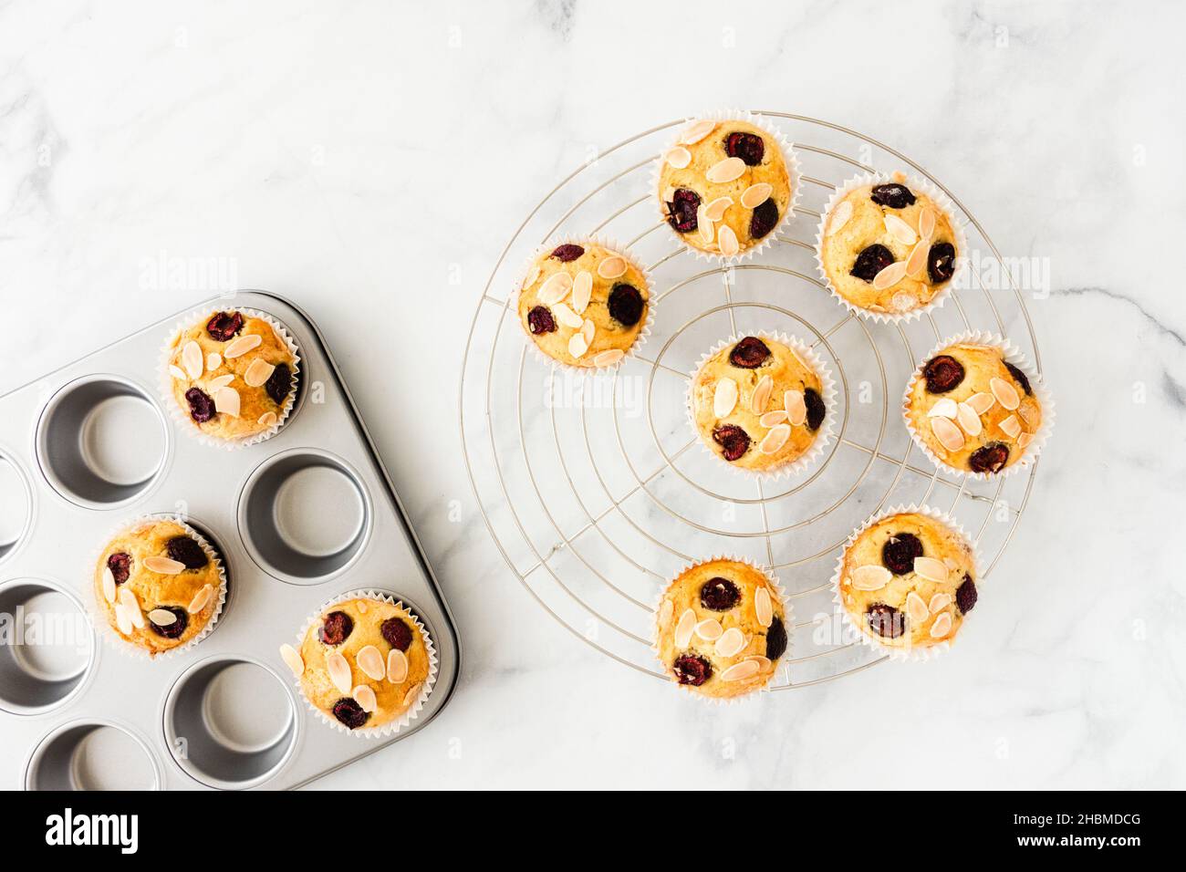 Cherry muffins in silver metal baking form and on cooling rack over ...