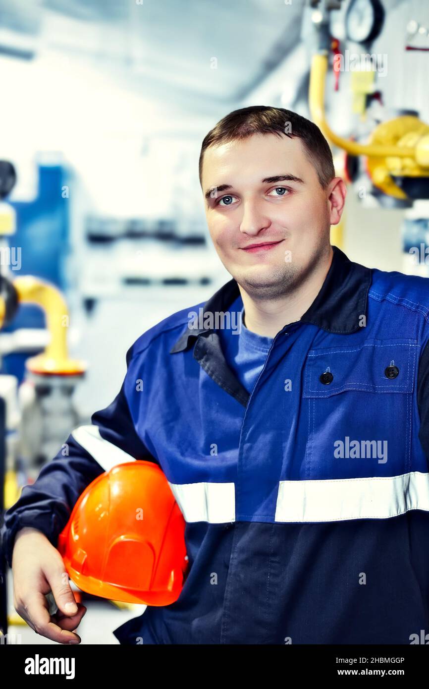 Portrait of young engineer in helmet in working environment at factory ...