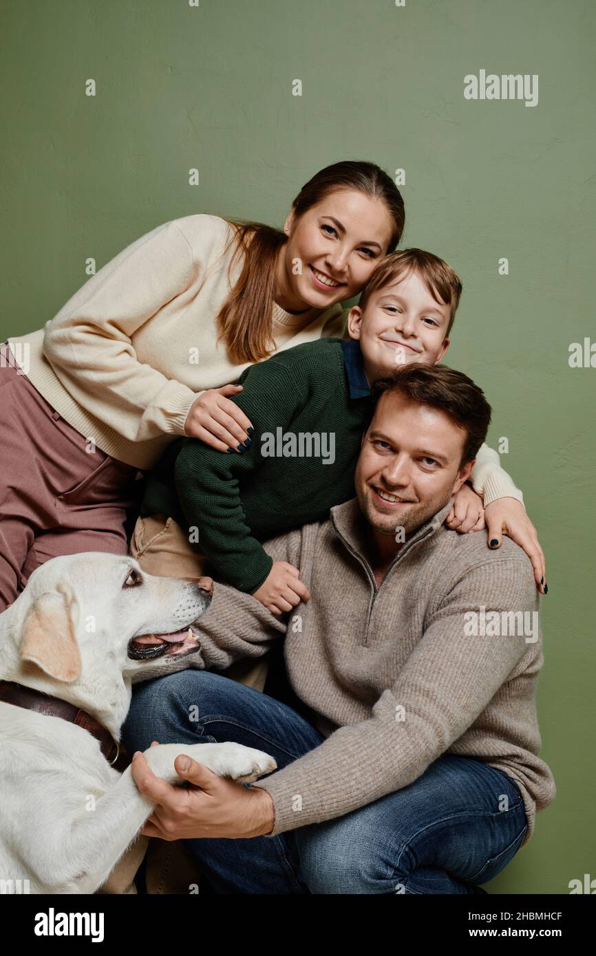 Vertical portrait of loving family with son and dog smiling at camera ...