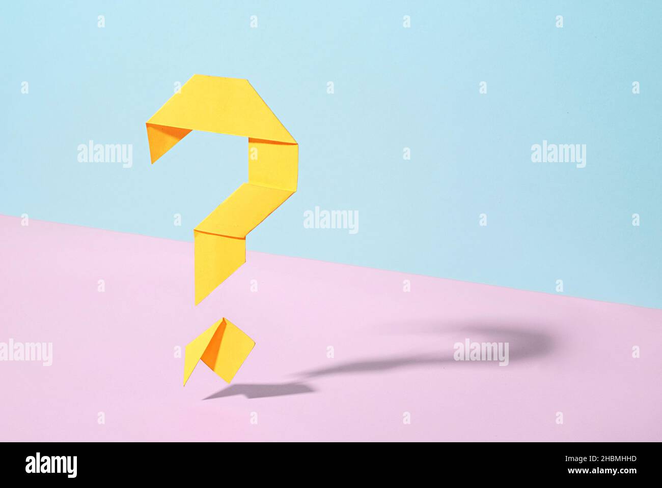 Floating yellow origami question mark throwing an offset shadow on a ...