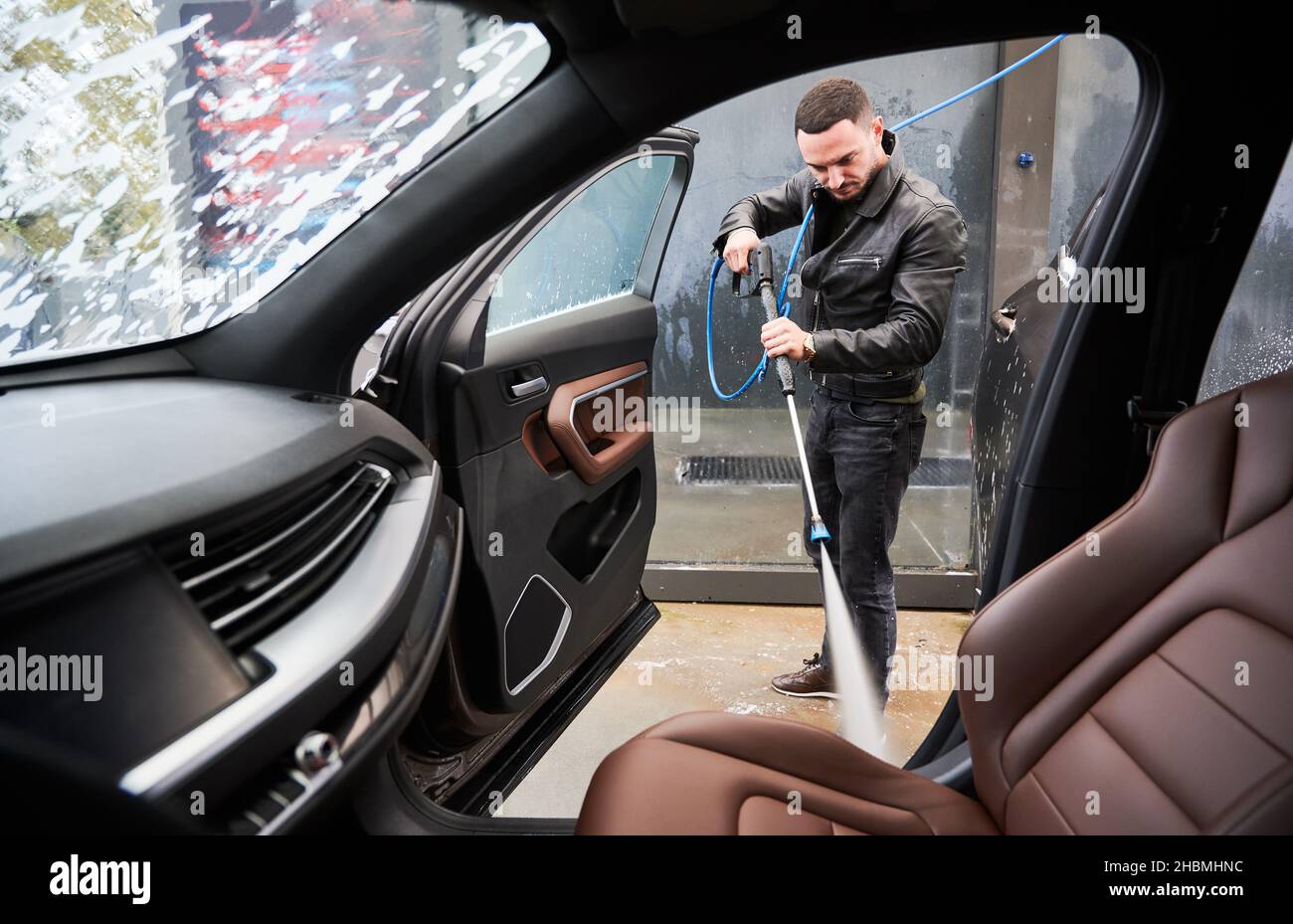 View from inside a car on young man washing car on carwash station ...