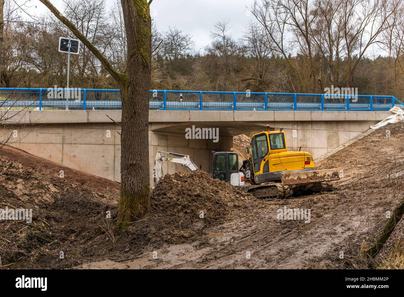 Excavator adjusts the terrain around the new bridge. Finishing work on ...