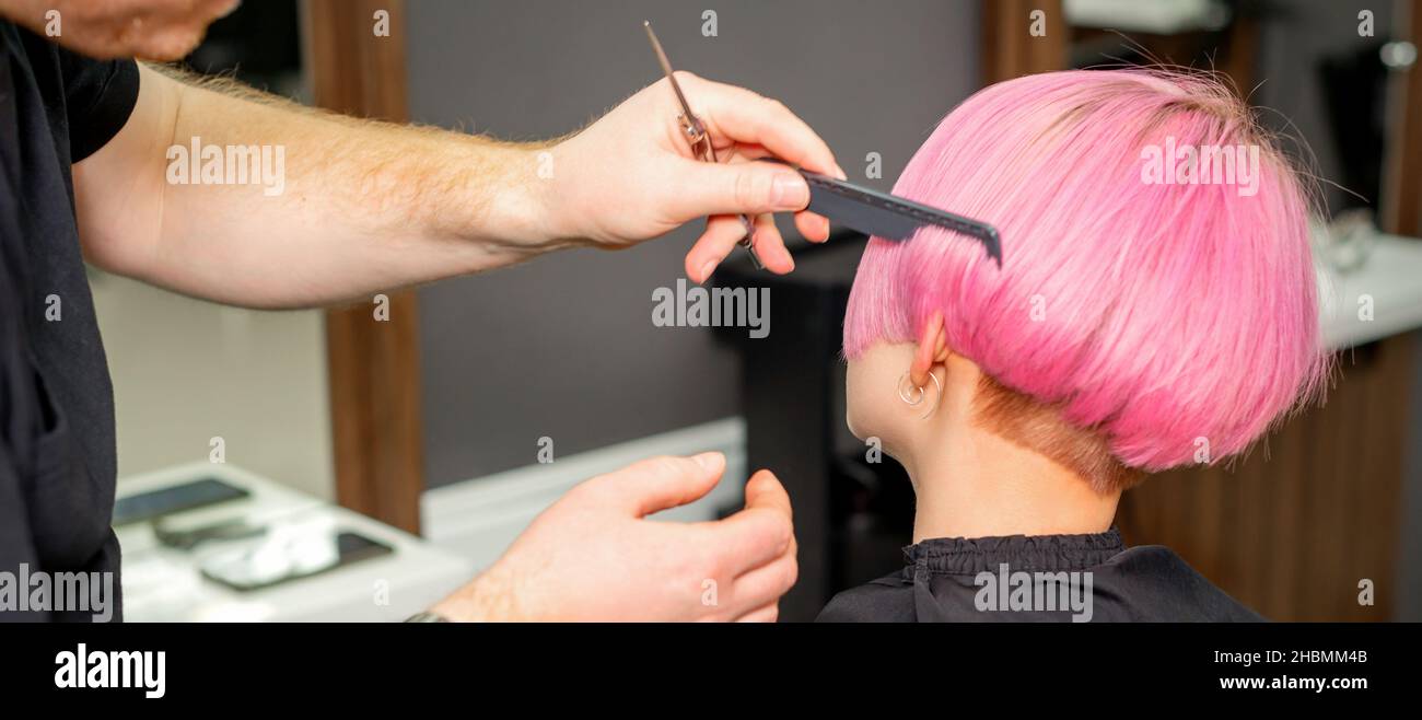 Hands of hairdresser combing hair making short pink hairstyle for a ...