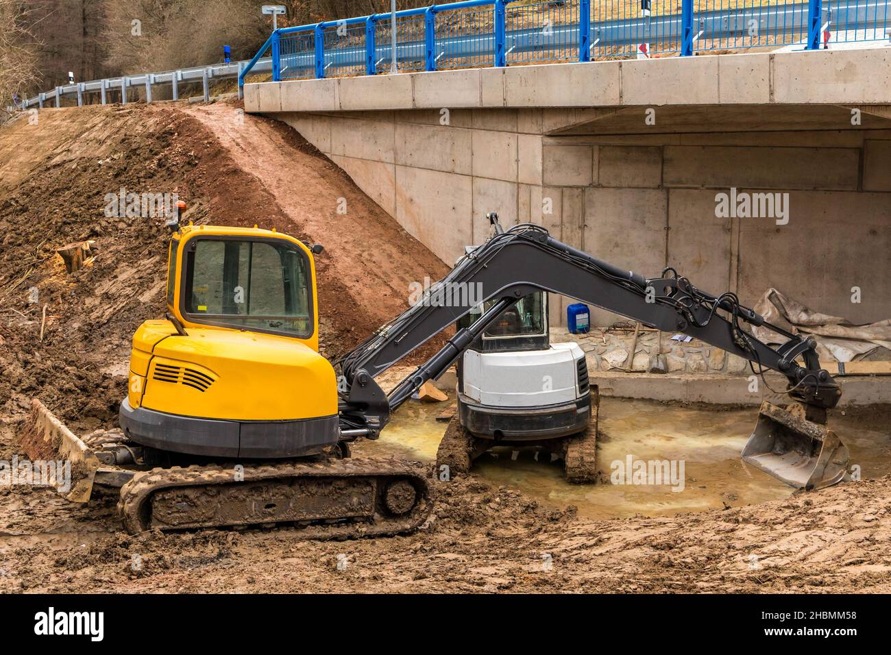 Excavator adjusts the terrain around the new bridge. Finishing work on ...
