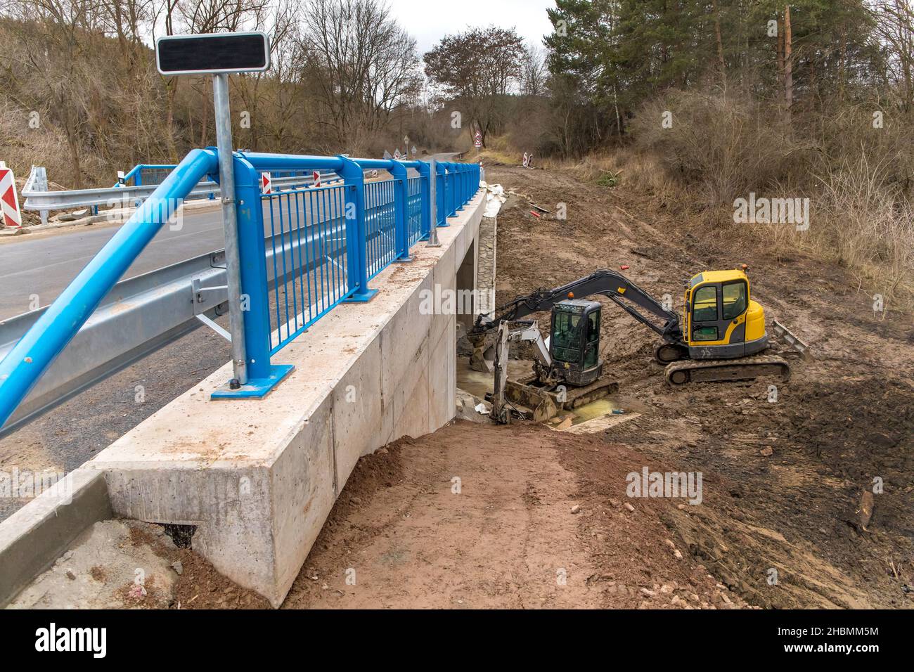 Excavator adjusts the terrain around the new bridge. Finishing work on ...