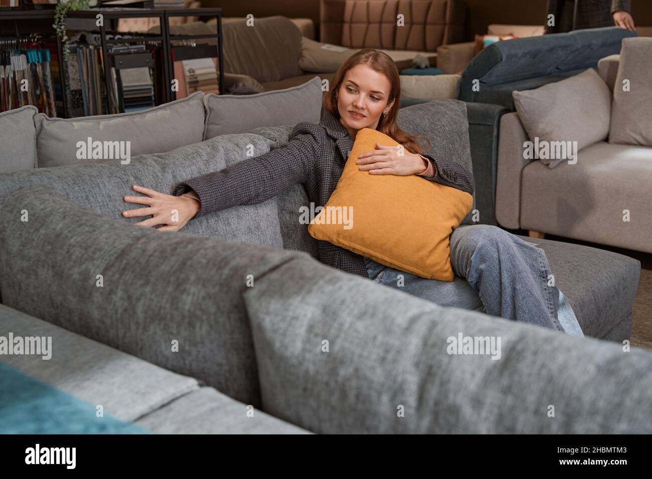 Concentrated lady selecting new couch in furniture store Stock Photo ...