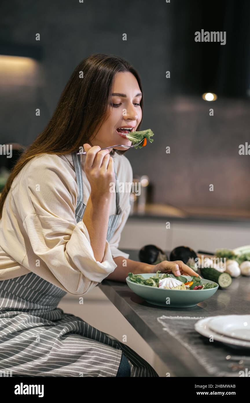 Young woman standing near the table with plate in hands Stock Photo - Alamy
