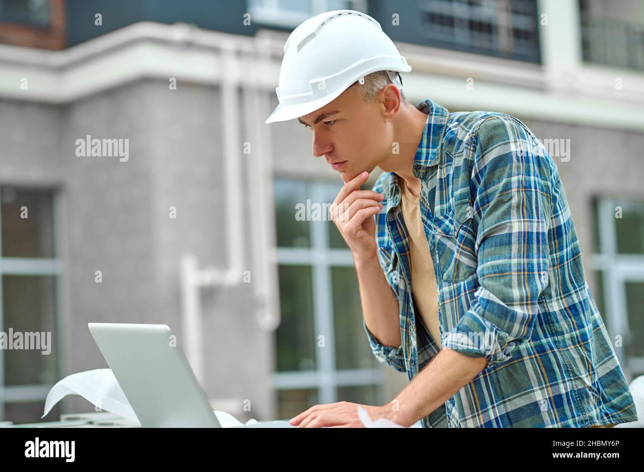 Profile of man looking into laptop at construction site Stock Photo - Alamy