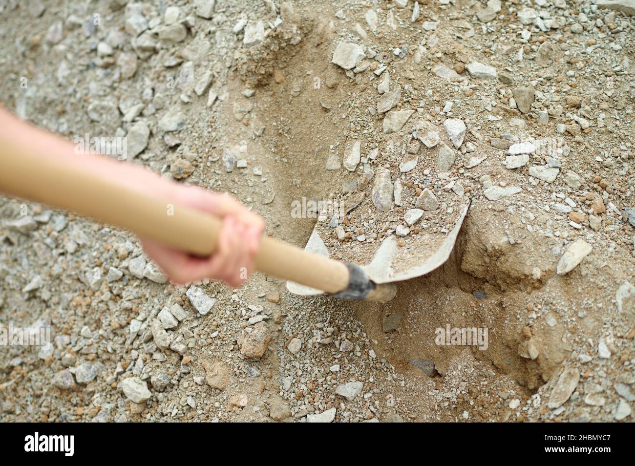 Hand of worker dripping gravel with shovel Stock Photo - Alamy