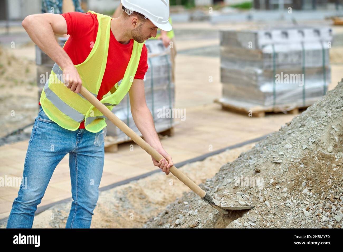 Man with shovel picking up rubble at construction site Stock Photo - Alamy