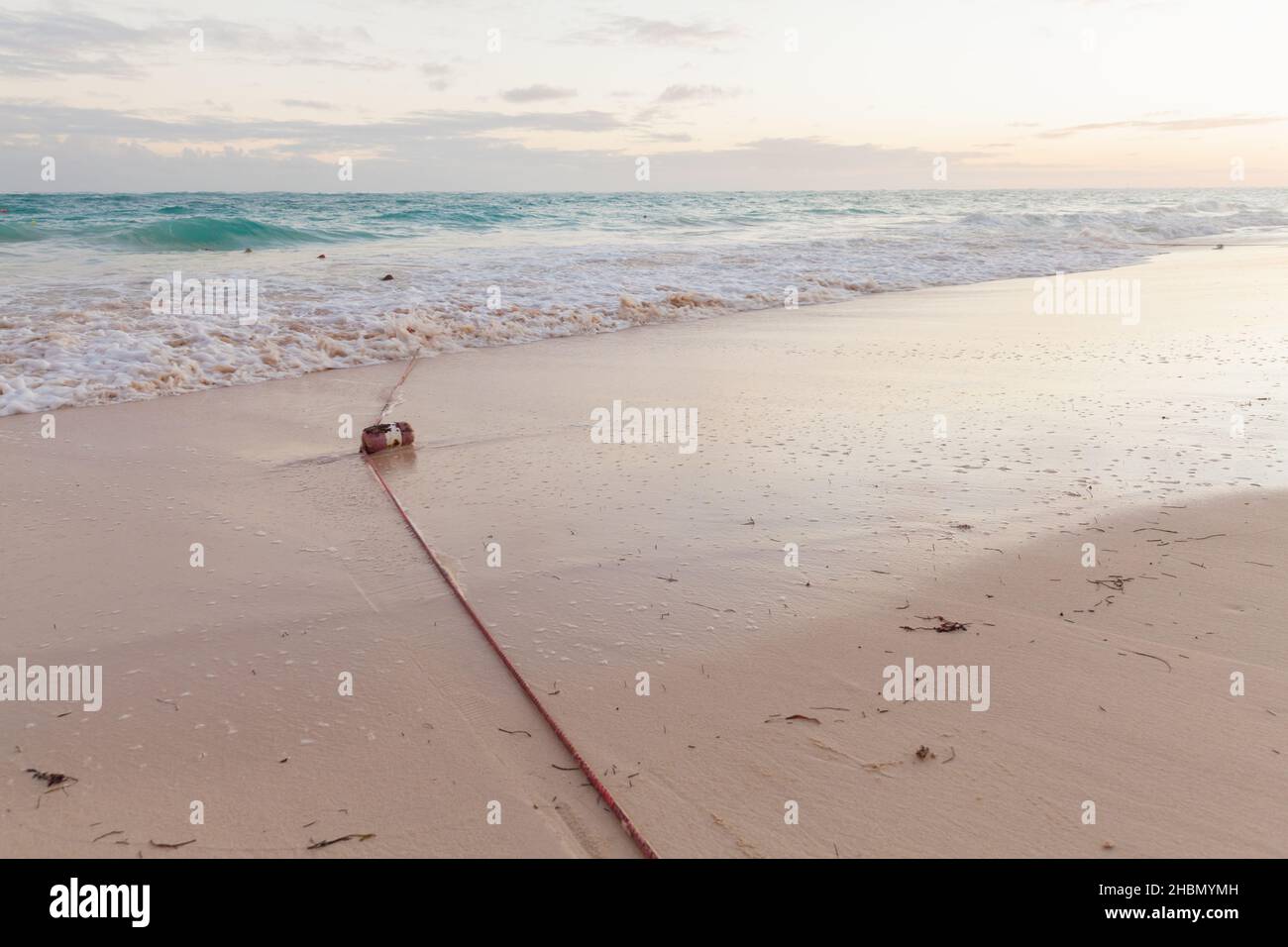 Coastal Caribbean landscape with a rope laying on an empty sandy coast ...