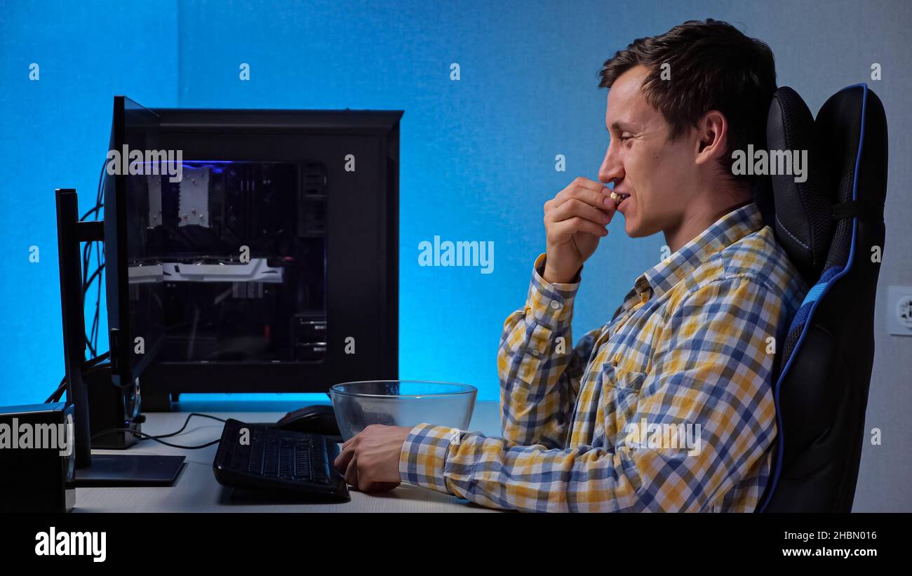 Young man watches stream with computer and eats popcorn Stock Photo - Alamy