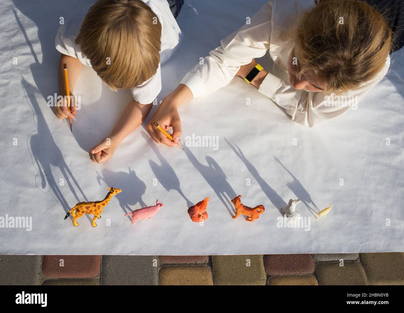 Two children - adult girl and small boy - draw with pencil around ...