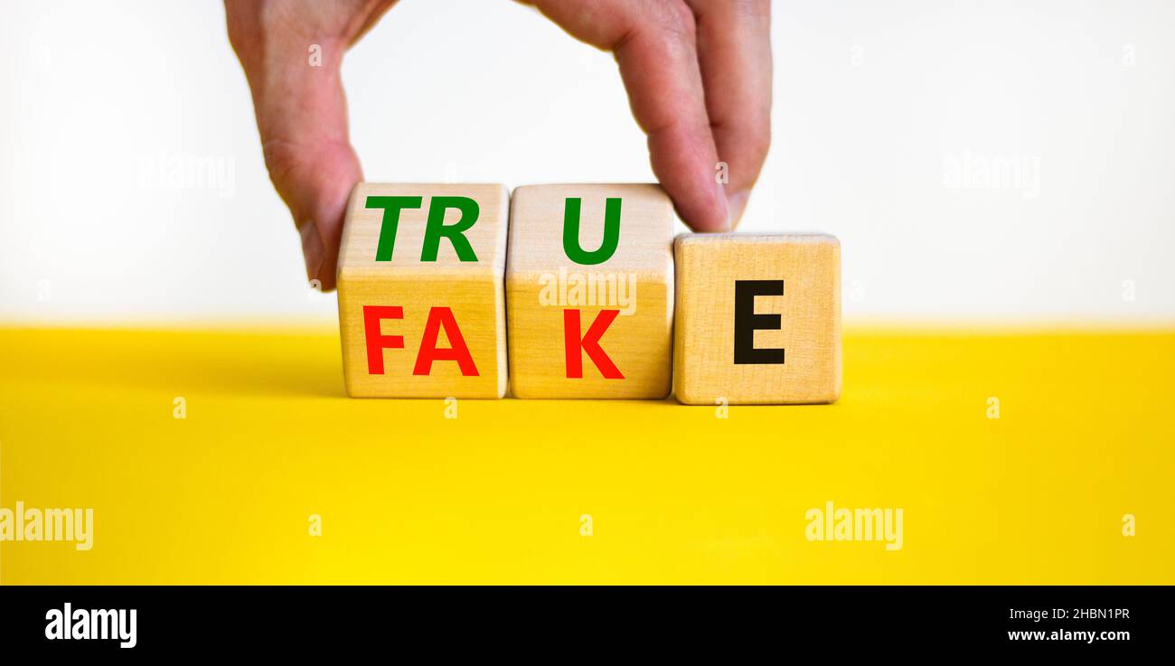 Fake or true symbol. Businessman turns wooden cubes and changes the ...