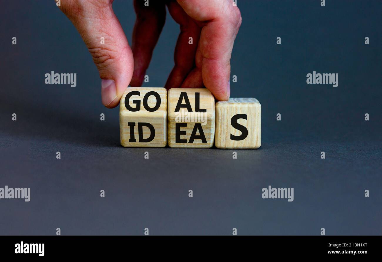Ideas and goals symbol. Businessman turns wooden cubes and changes the ...