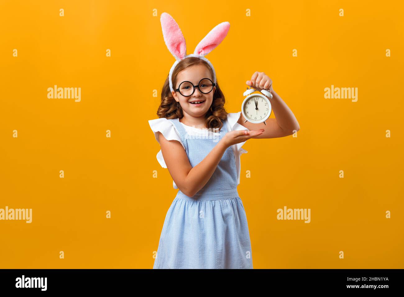 Happy little girl in Easter bunny ears on isolated yellow background ...