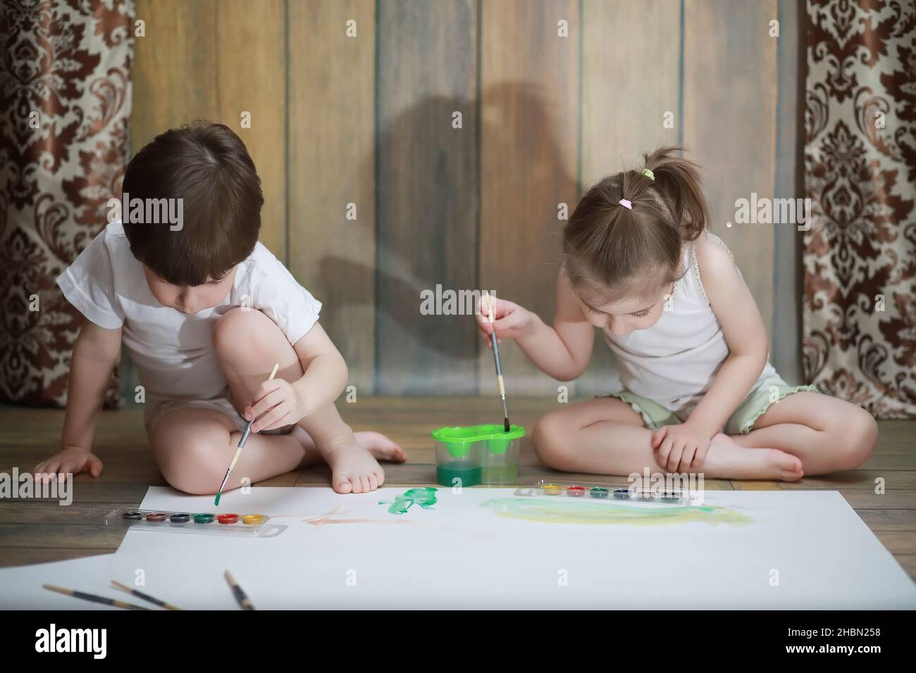 Little children paint on a large sheet of paper on the floor Stock ...