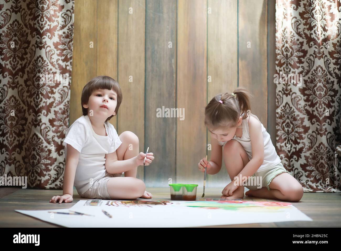 Little children paint on a large sheet of paper on the floor Stock ...