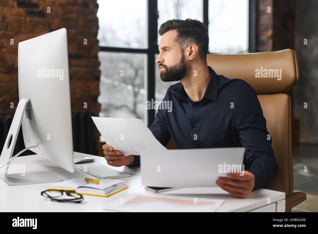 Clever and concentrated caucasian guy is doing paperwork. Man looking ...