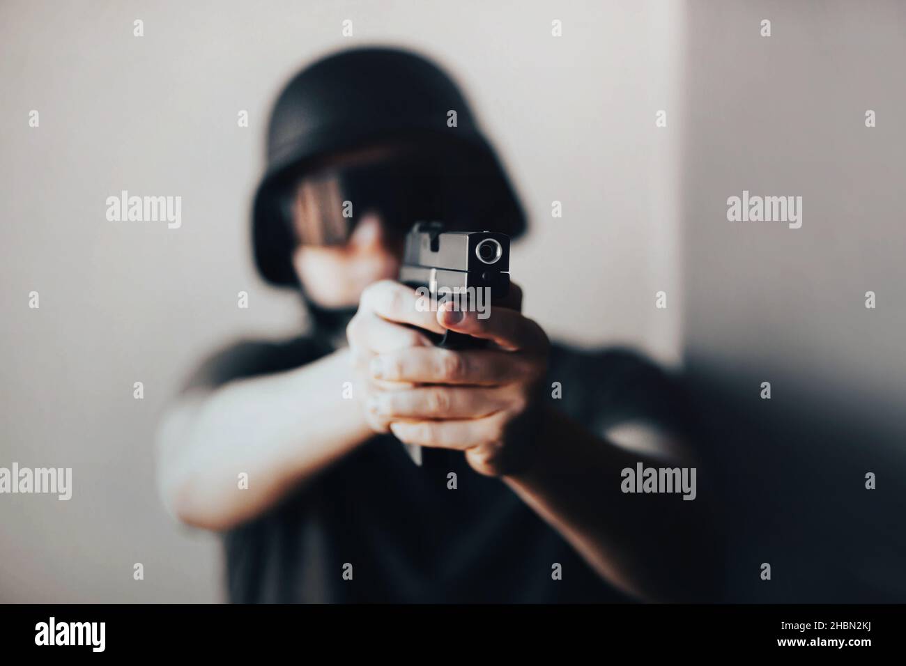 A man in a black helmet stands with a gun in his hands and takes aim ...