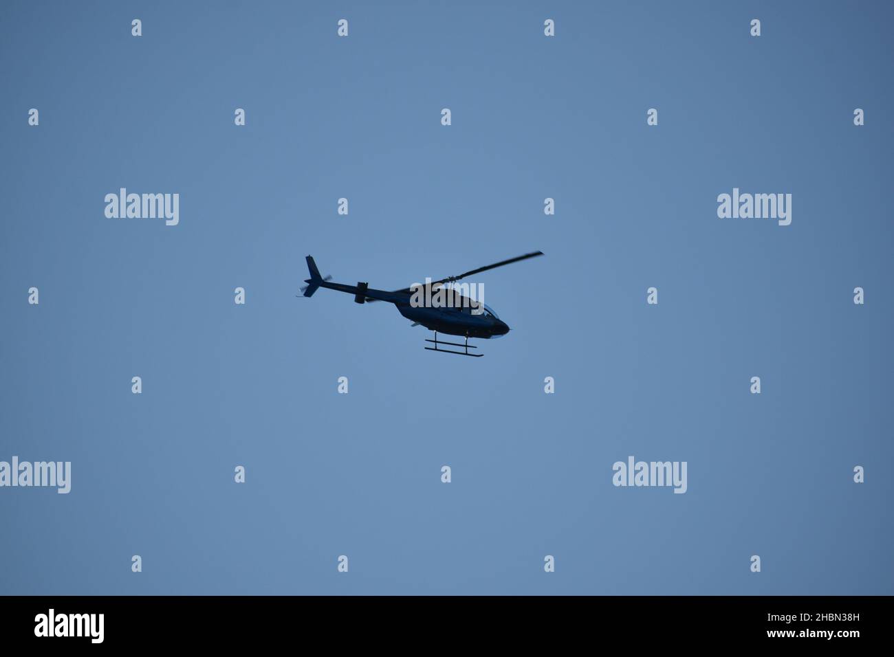 Side view of a helicopter tilting away against a clear blue sky Stock ...