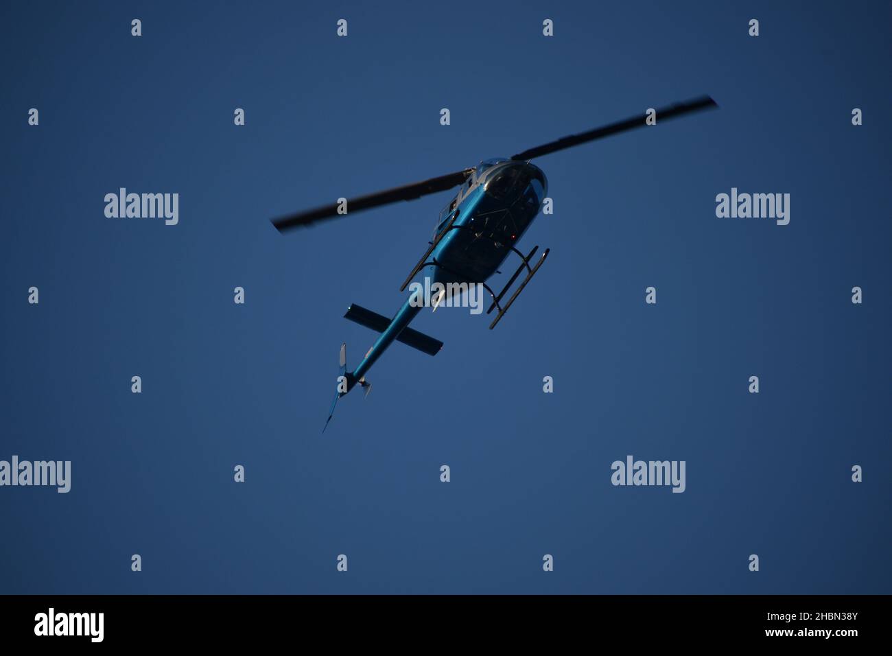 Bottom view of blue helicopter flying overhead Stock Photo - Alamy