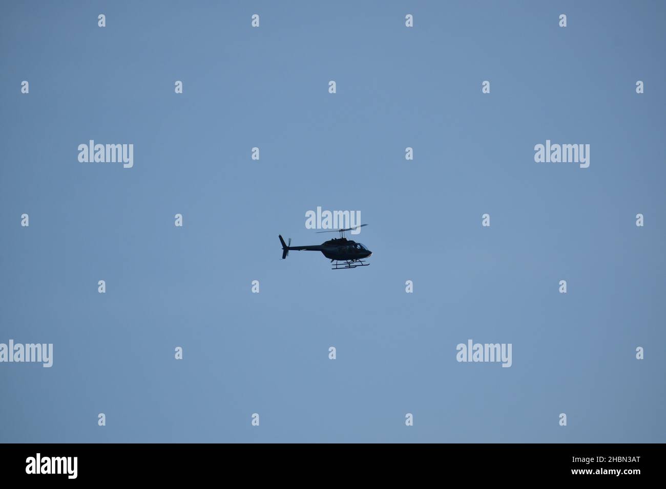 Side view of a helicopter hovering over a clear blue sky Stock Photo ...