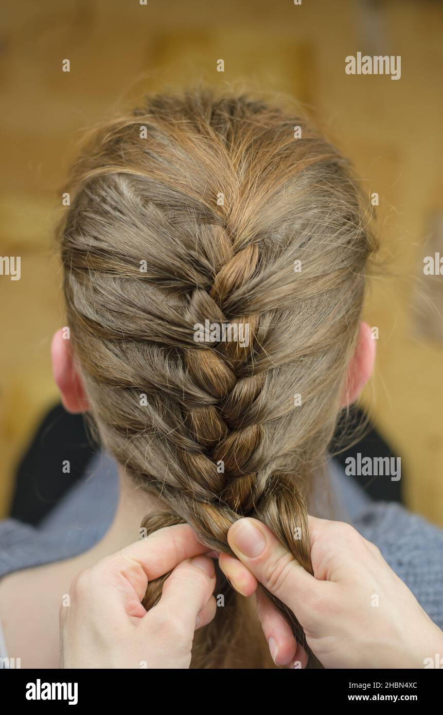 A woman braids a pigtail for a red-haired girl. Hair weaving hairstyles ...