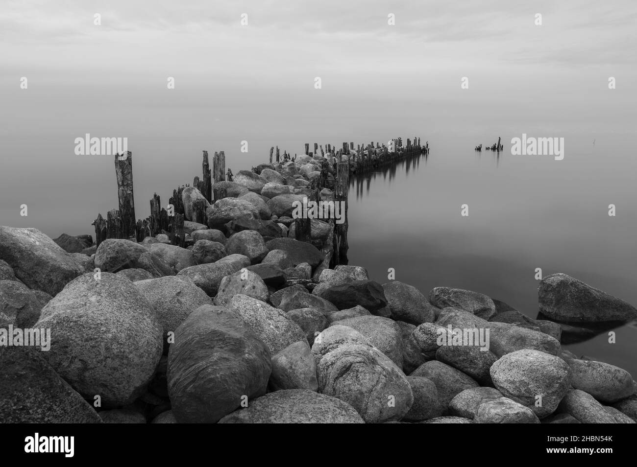 an old pier made of stones and wooden legs is left with metal screeds ...