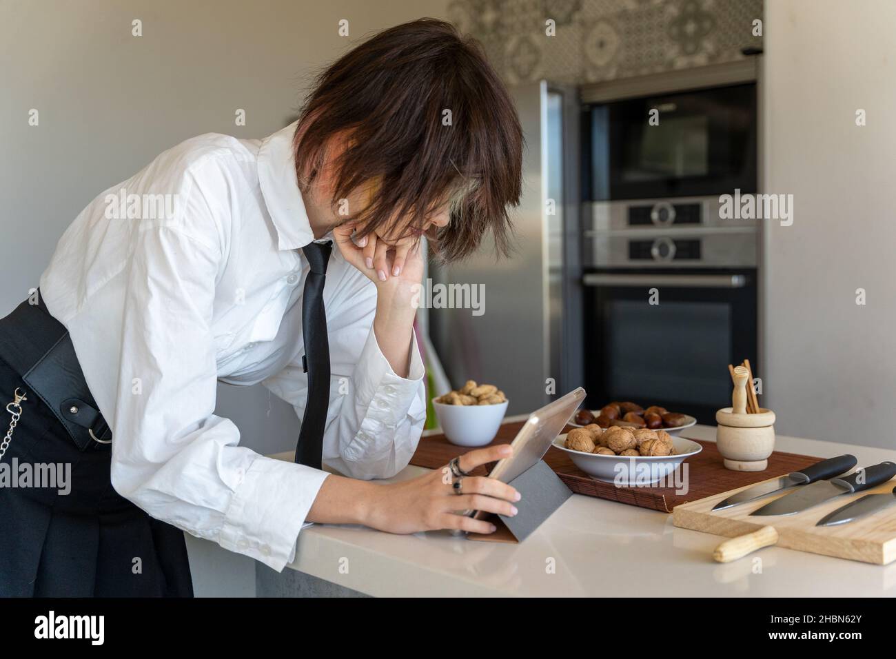 executive woman looking at a recipe on a tablet, standing in the ...
