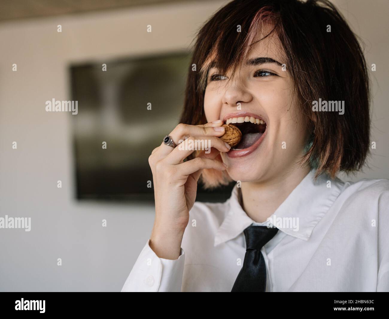 woman laughing while trying to bite a walnut with her mouth, horizontal ...
