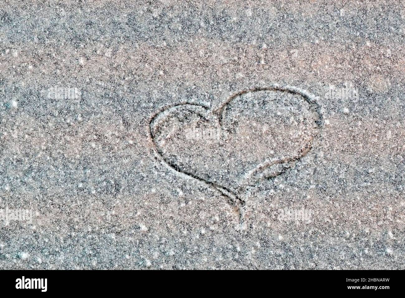 Heart drawn by the hand of a man on a marble wall in a blue close-up ...
