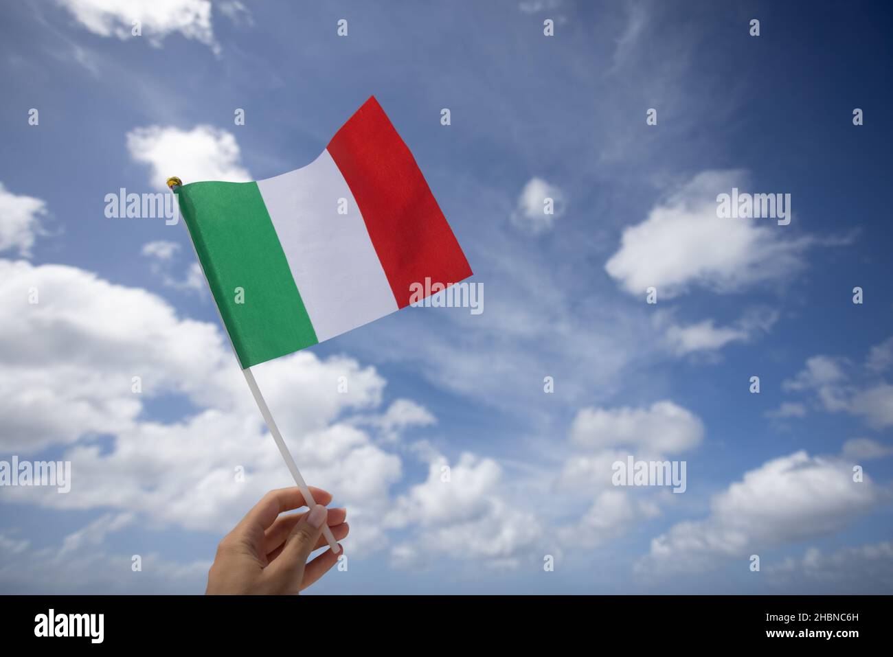 Italian flag waving in the wind in a female hand on a blue sky with ...