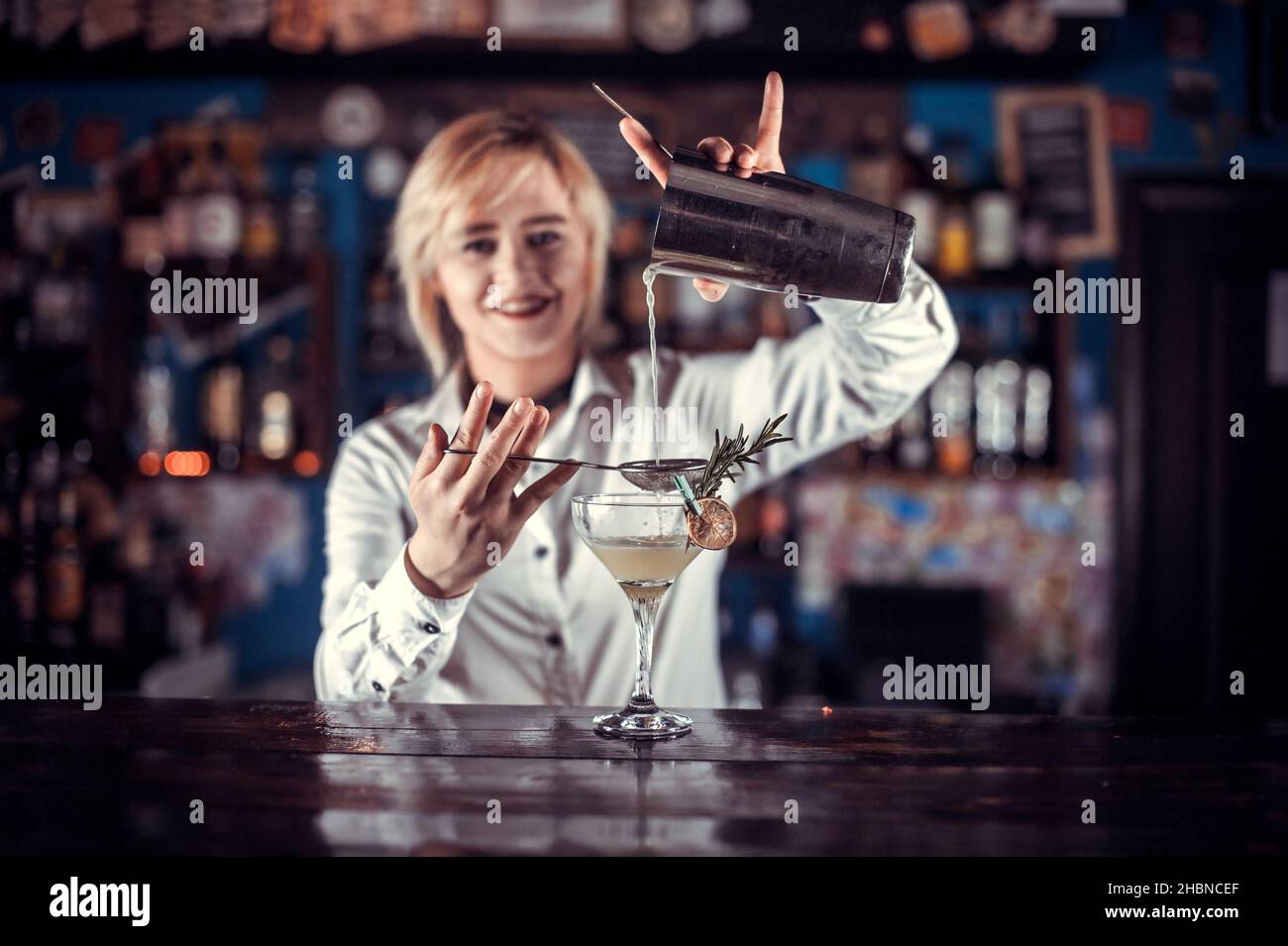 Charming barmaid places the finishing touches on a drink in the night ...