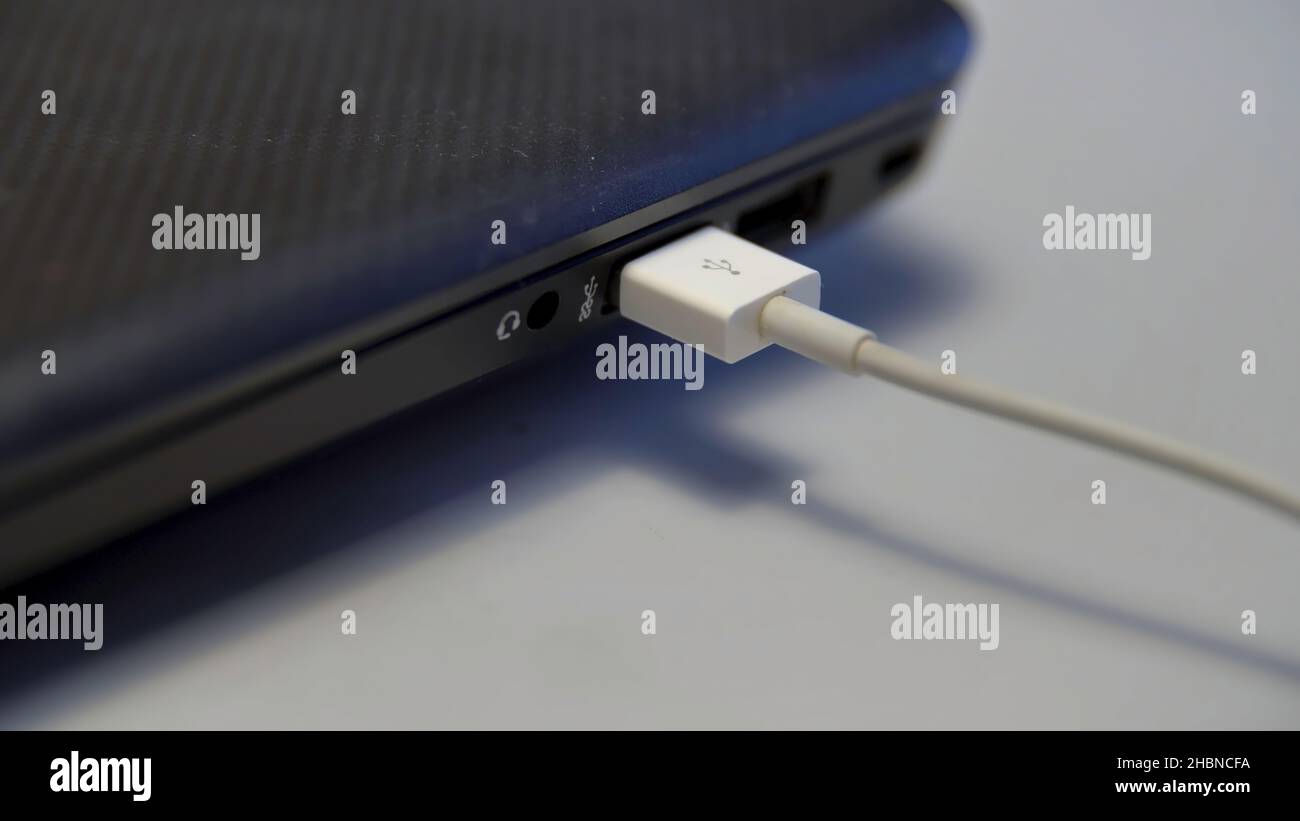 Hand inserting white USB cable into laptop isolated on white background ...