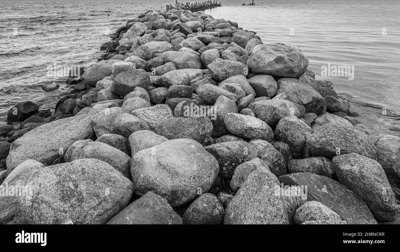 an old pier made of stones and wooden legs is left with metal screeds ...
