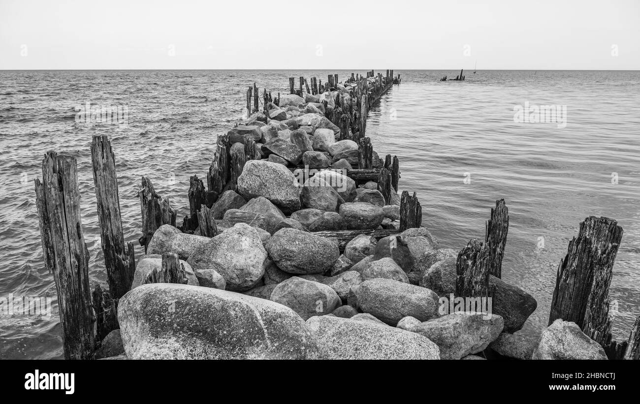 an old pier made of stones and wooden legs is left with metal screeds ...