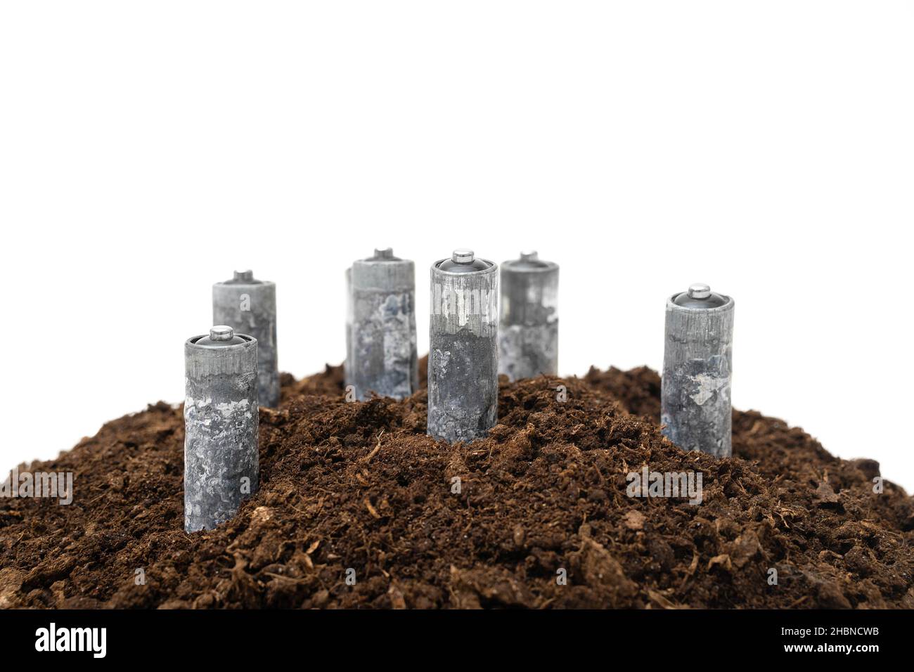 Heavily corroded used batteries sticking out of a soil pile isolated on ...