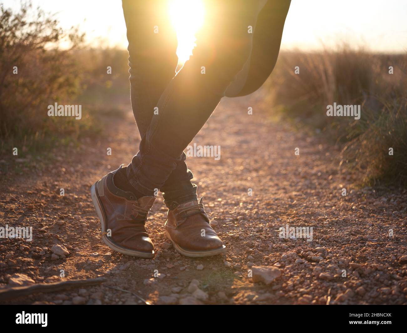person's legs crossed with the sun passing through them at sunset in ...