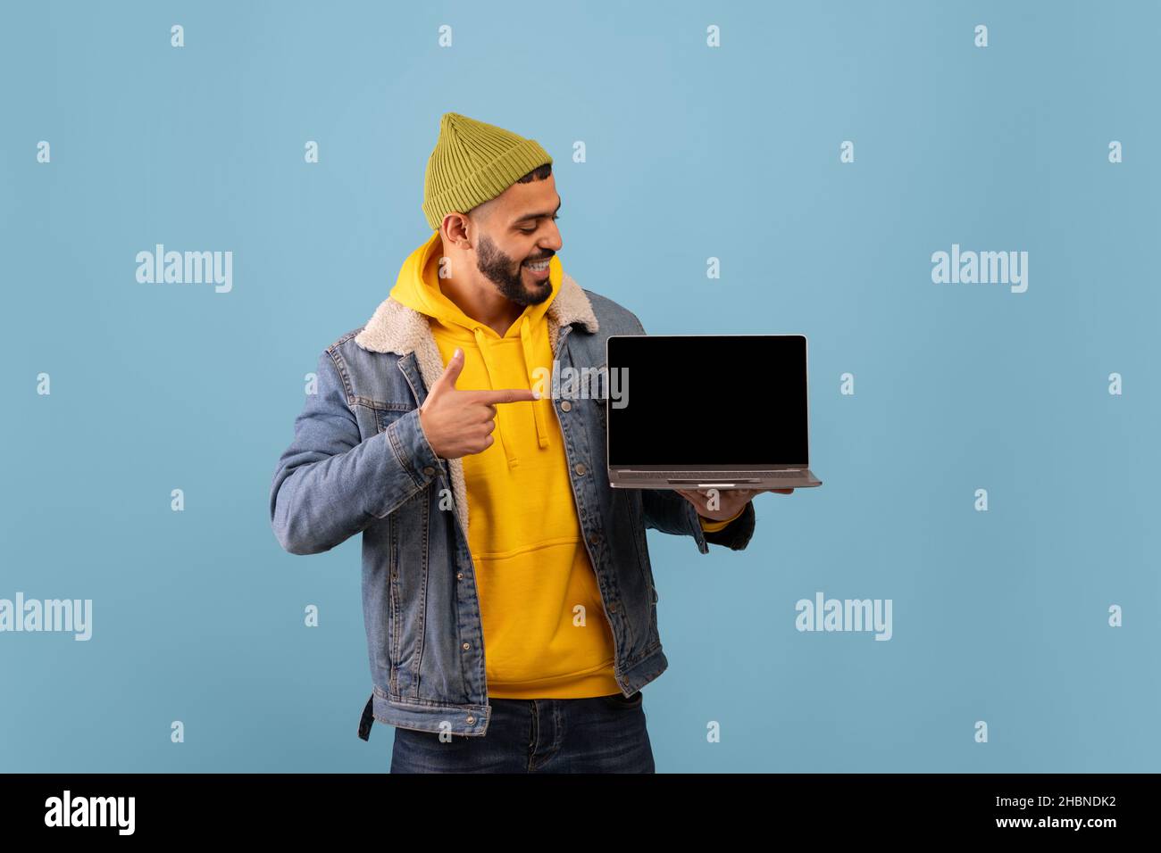 Stylish arab man pointing at blank laptop screen with space for your ...