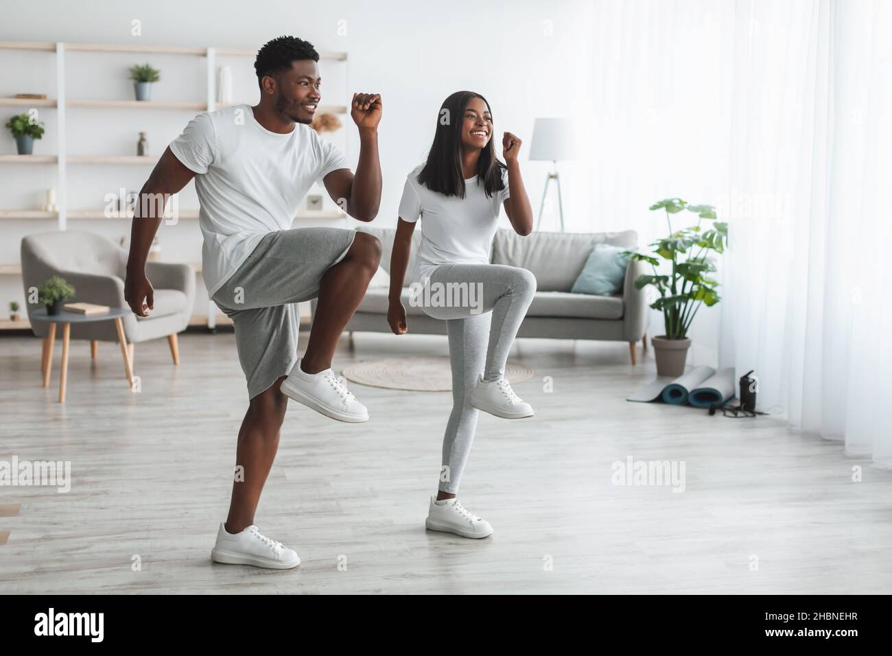 Young black couple doing high knee exercise Stock Photo - Alamy