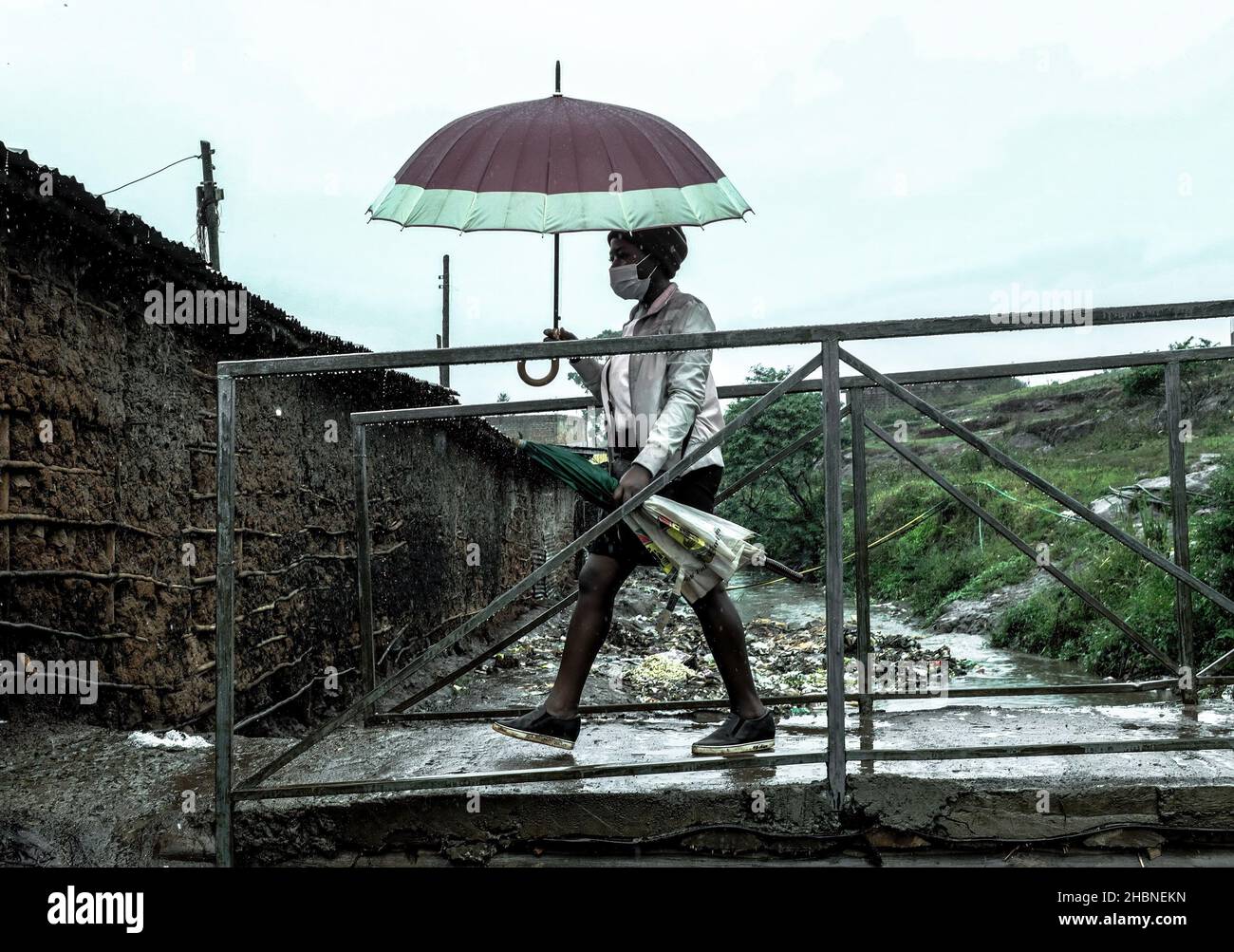 Nairobi, Kenya. 2nd Dec, 2021. A woman shelters from the rain beneath ...