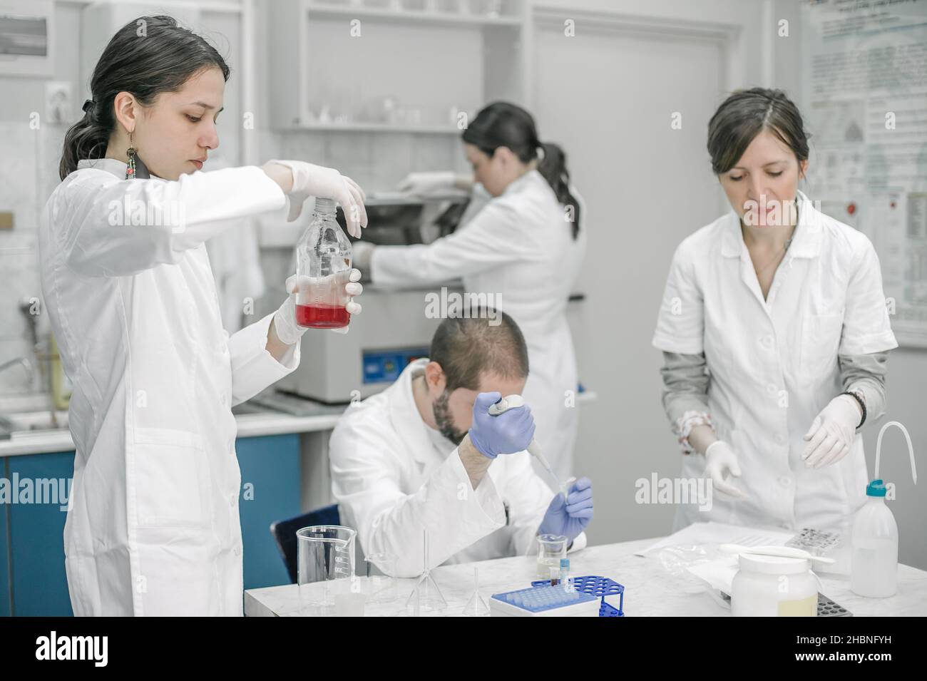 Group of scientists working with liquid test tube samples in laboratory ...