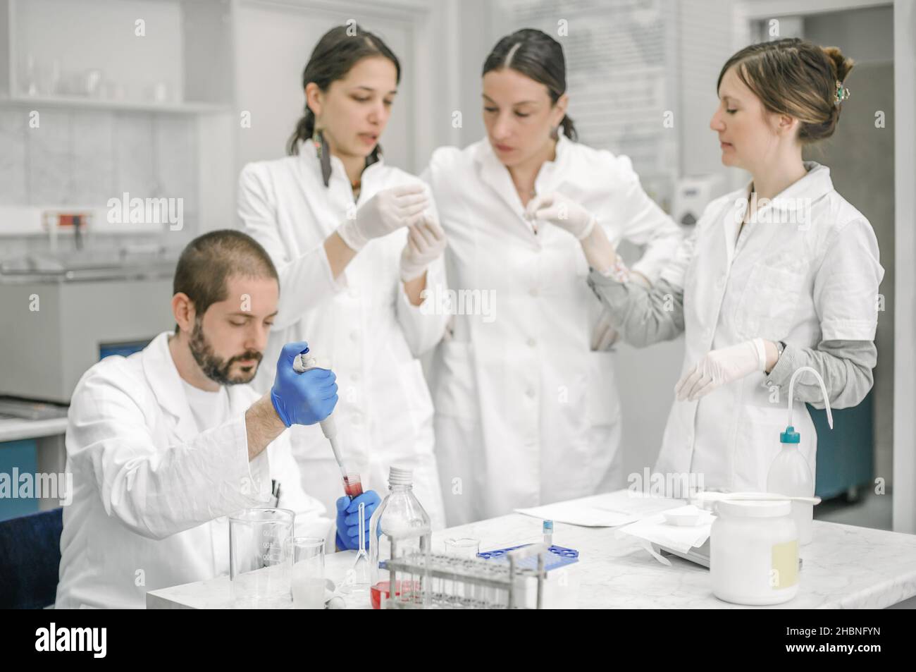 Group of scientists working with liquid test tube samples in laboratory ...