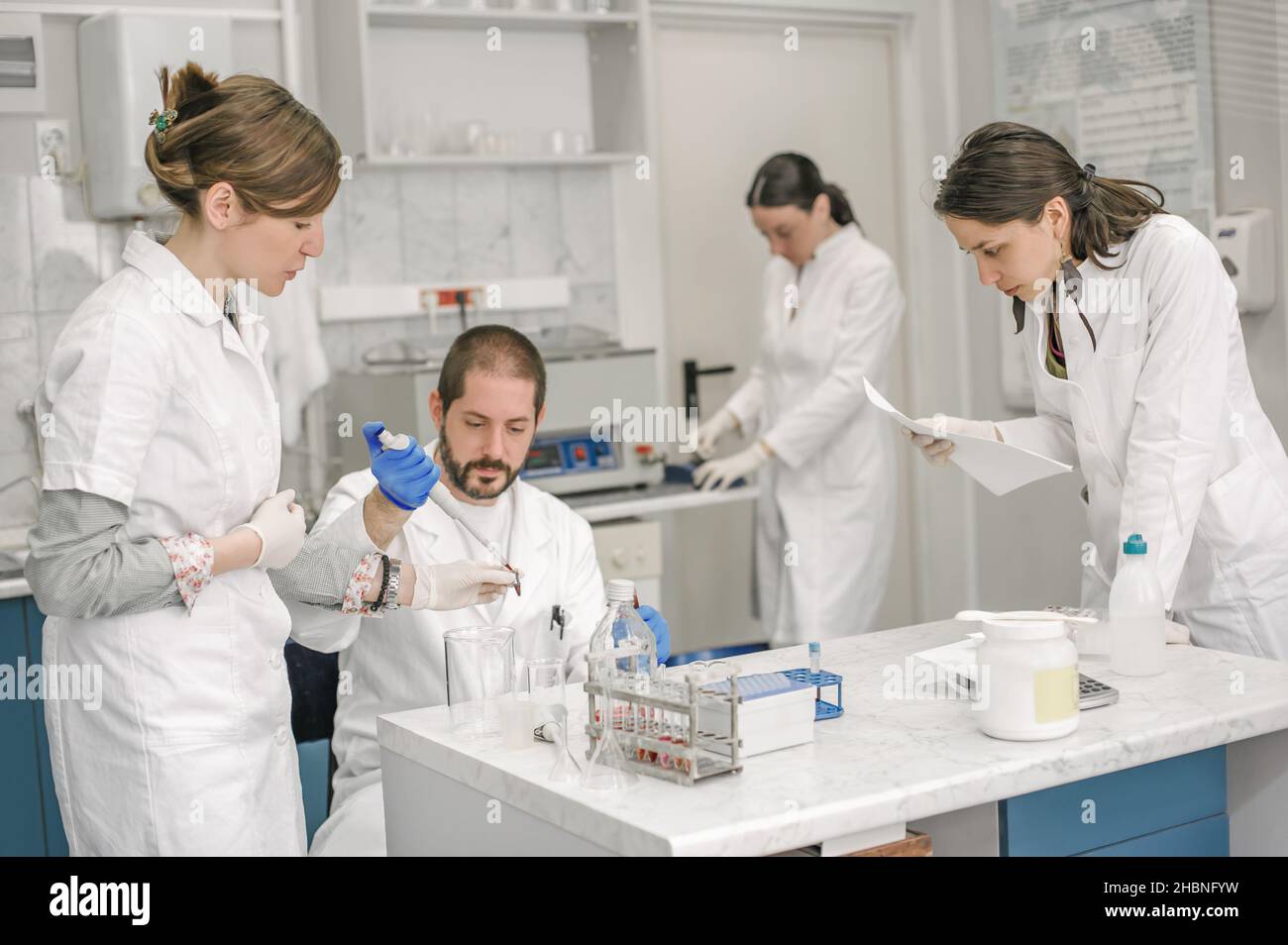 Group of scientists working with liquid test tube samples in laboratory ...