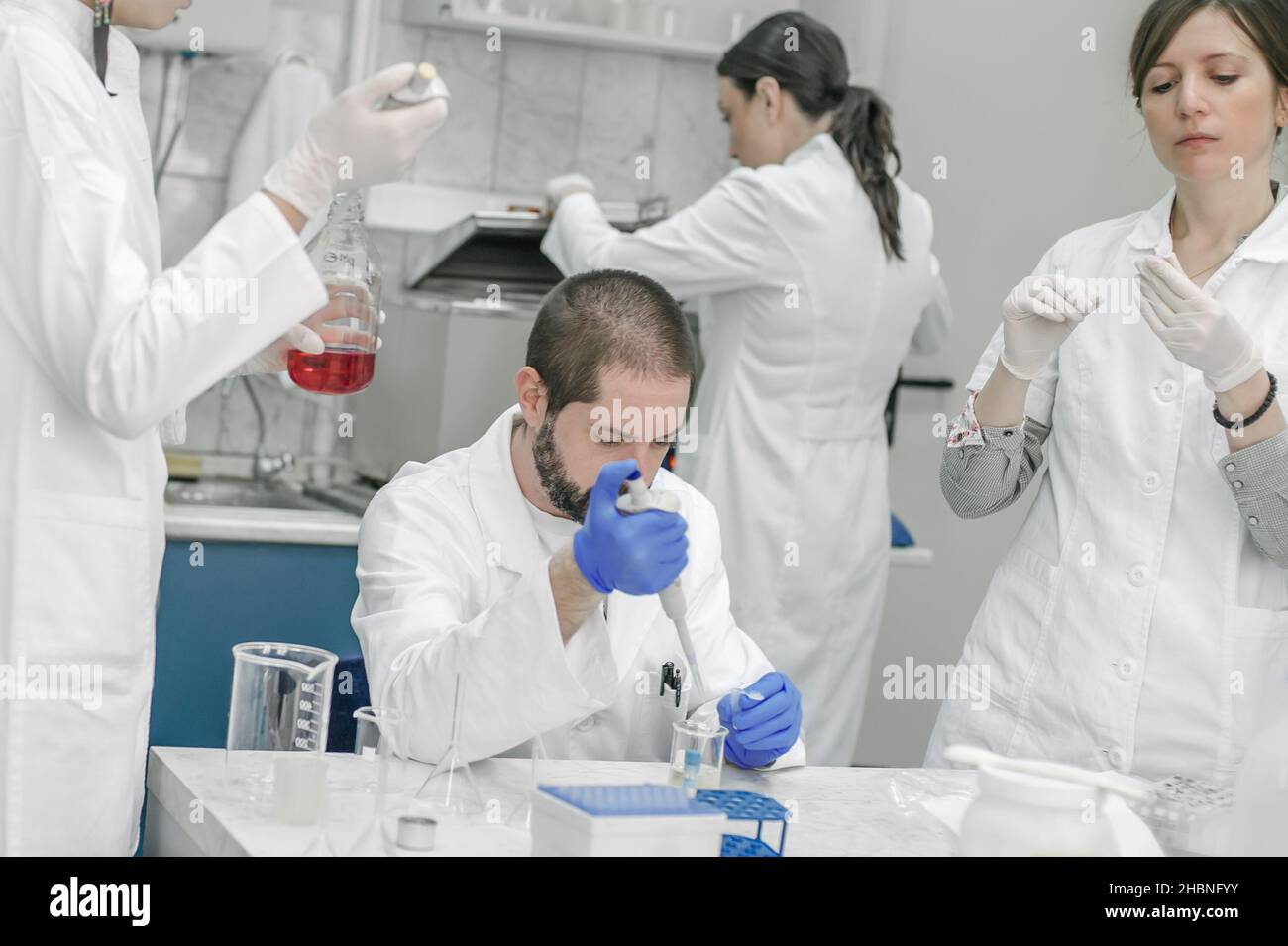 Group of scientists working with liquid test tube samples in laboratory ...