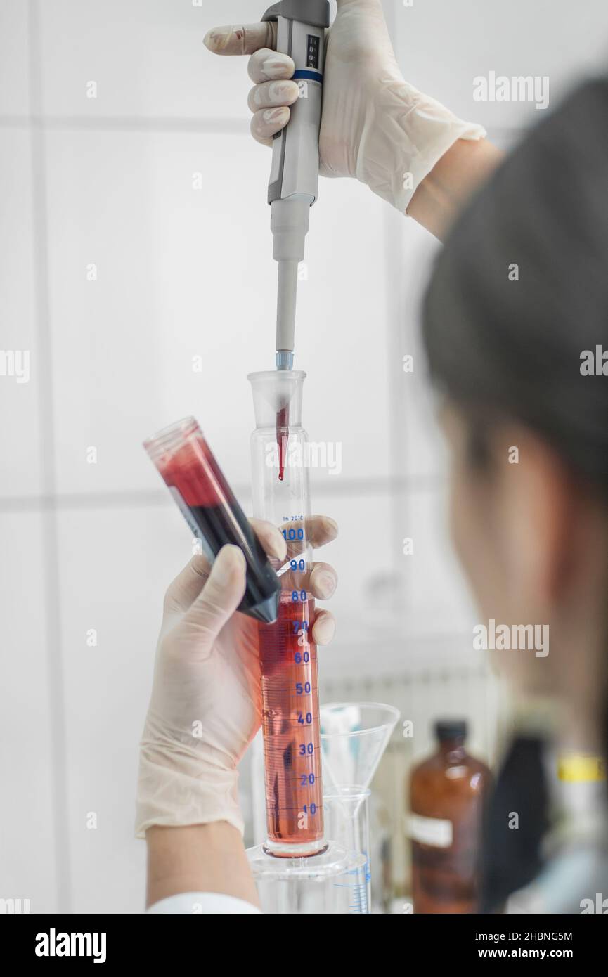 Medical laboratory scientists in the laboratory filling test tubes with ...